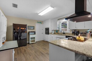 Uma cozinha moderna com geladeira de aço inoxidável, forno embutido e bancada de granito.