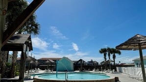 Uma área de piscina com piscina circular, cadeiras de descanso e guarda-sóis.