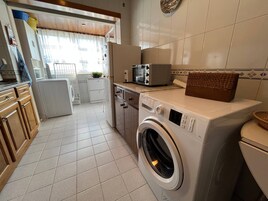 Uma cozinha compacta com máquina de lavar, micro-ondas e frigorífico pequeno.