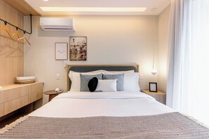 Quarto de hotel com cama, mesas de cabeceira, ar condicionado fixado na parede e um cabideiro.