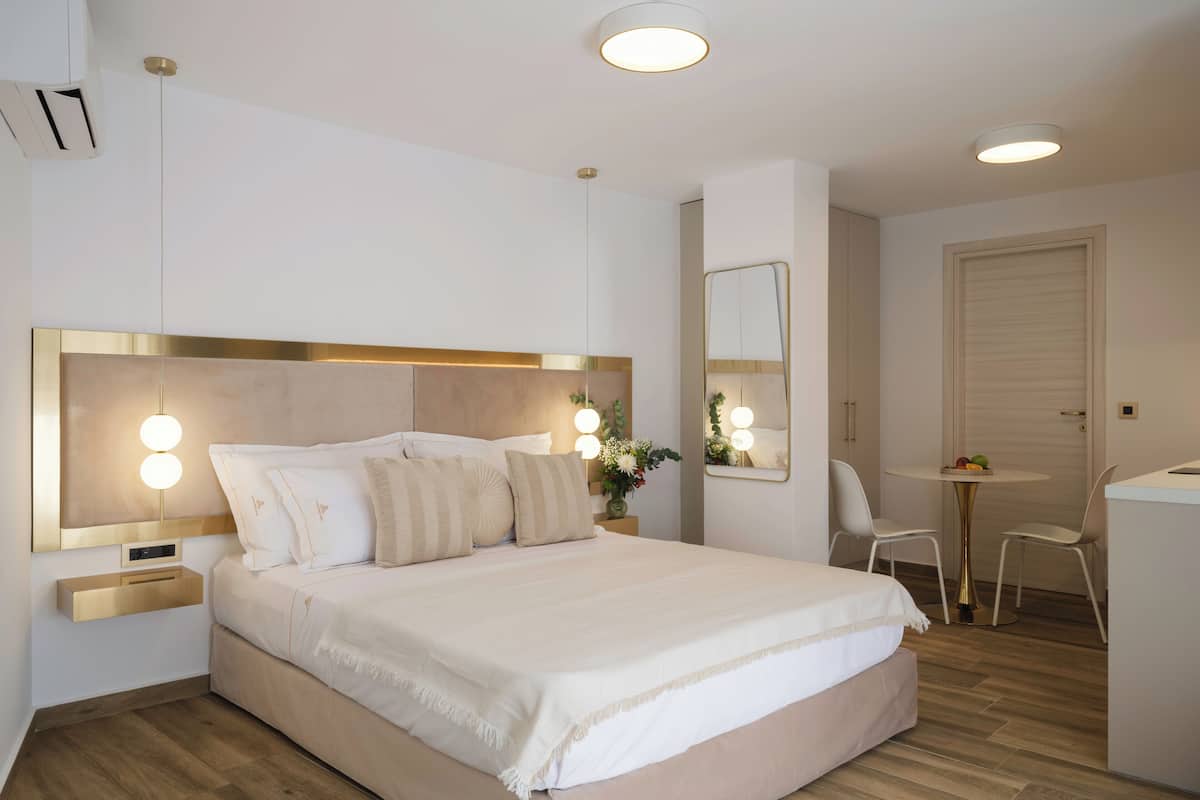 Quarto moderno com uma cama grande, mesas de cabeceira, um espelho, uma mesinha com frutas e uma cadeira.