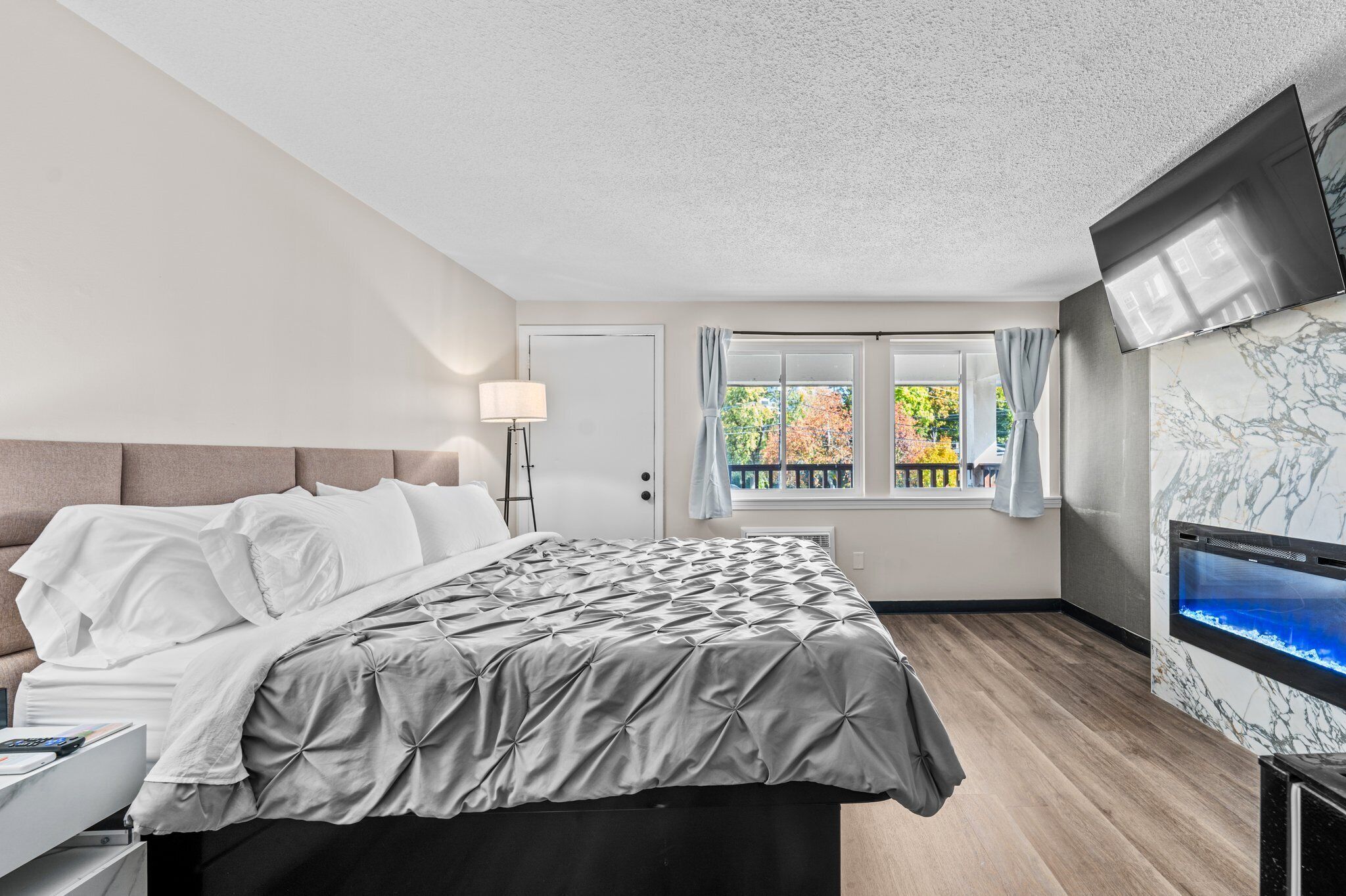 Quarto de hotel moderno com cama, televisão, lareira e janela com vista para o exterior.