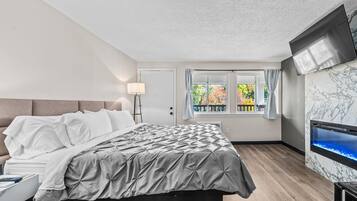 Quarto de hotel moderno com cama, televisão, lareira e janela com vista para o exterior.