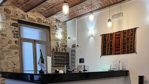 Uma área de recepção com parede de pedra, piso de azulejos e um balcão com uma bandeira.