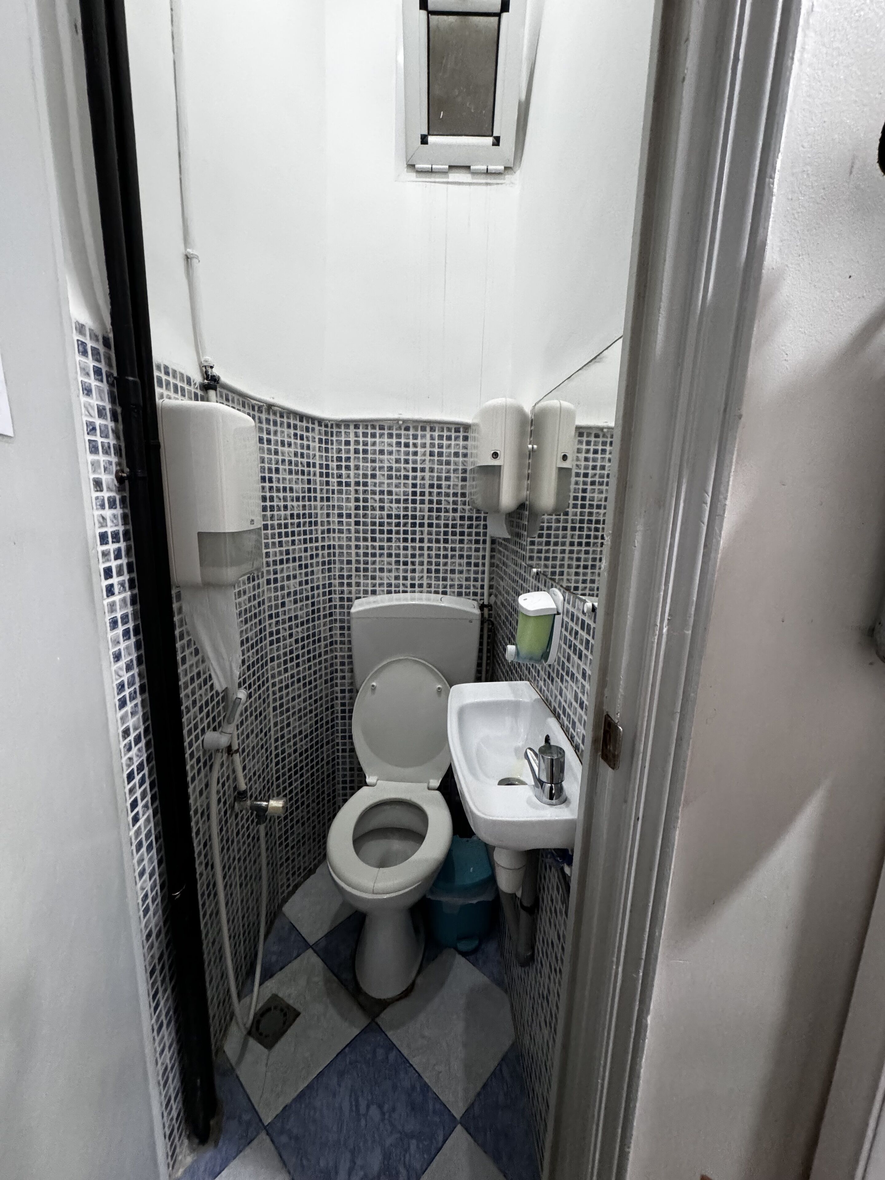 Um banheiro pequeno com vaso sanitário, pia e chuveiro.