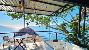 Área externa coberta com hidromassagem, assentos e vista para o mar.