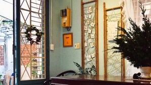 Uma área de refeições com uma mesa e cadeiras de madeira, uma grinalda decorativa na porta e uma parede com quadros e um calendário.