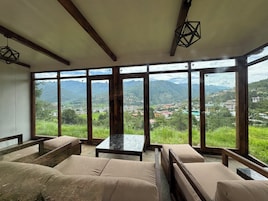 Quarto com grandes janelas que oferecem vista para uma paisagem montanhosa.