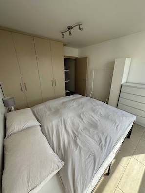 Quarto com cama, guarda-roupa e espelho.