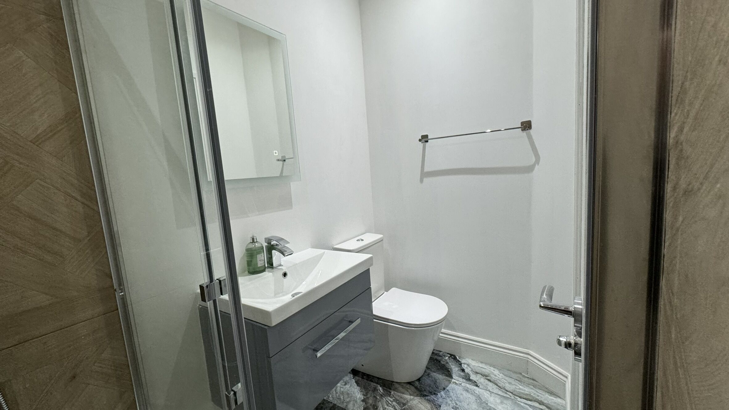 Uma casa de banho moderna com chuveiro em cabine de vidro, lavatório branco e sanita.