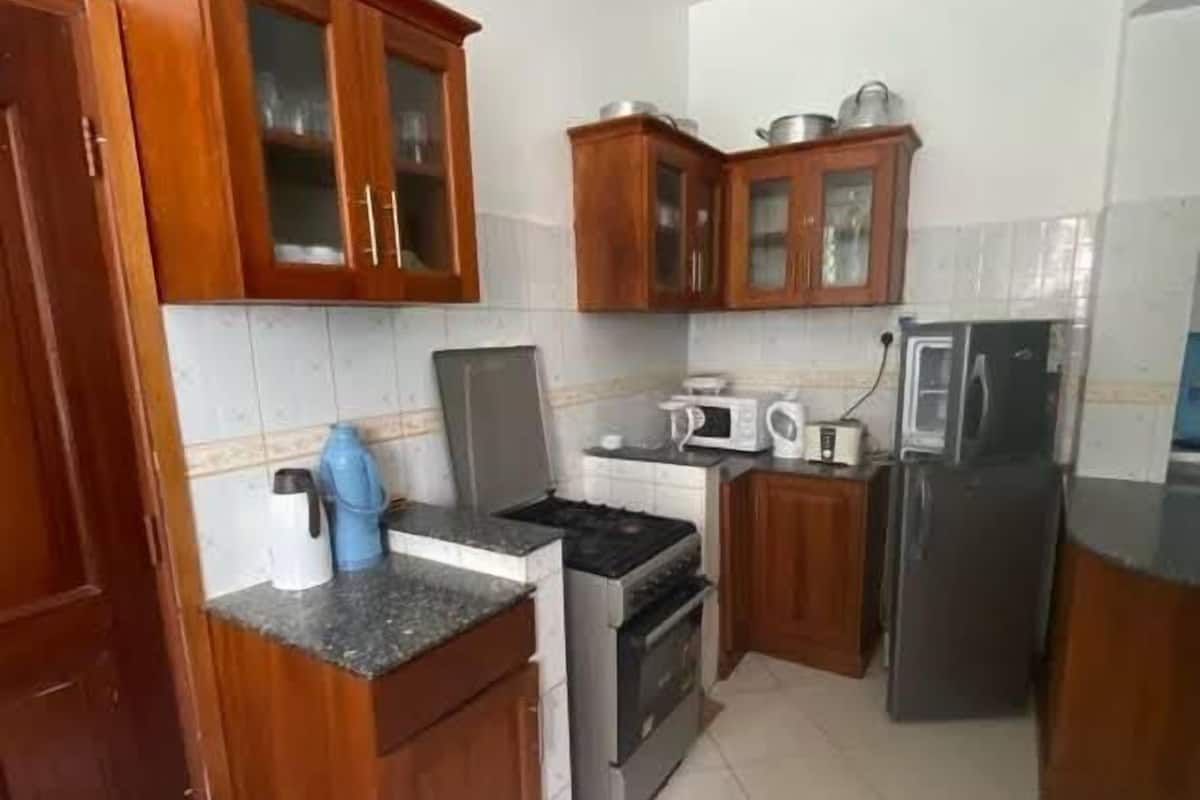 Uma cozinha com armários de madeira, fogão a gás, forno, micro-ondas e geladeira.