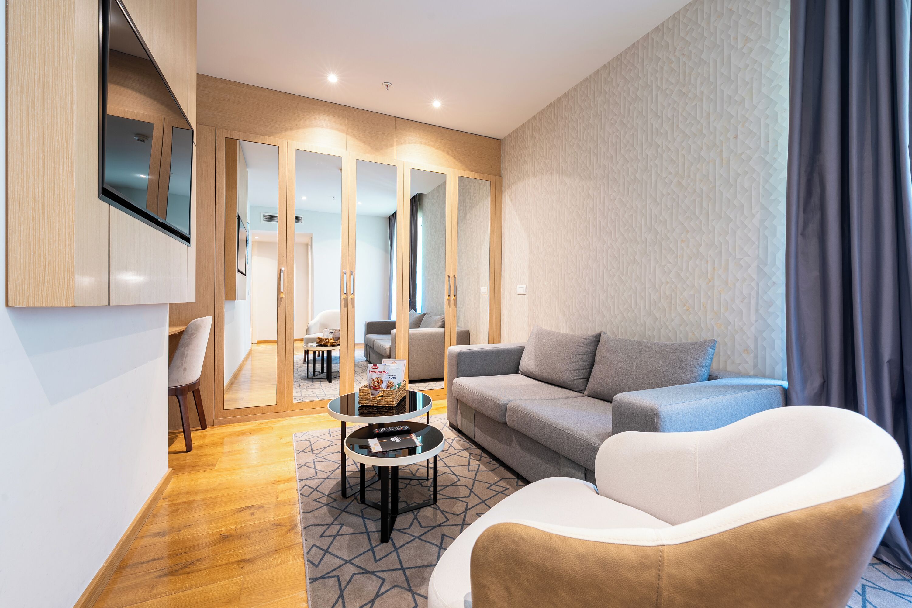 Uma sala de estar moderna com sofá, poltrona e uma mesinha com uma cesta.