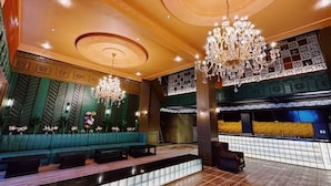 Um hall amplo com área de estar verde, balcão de recepção e um grande candelabro.