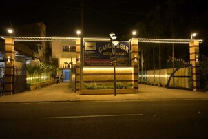 Uma entrada gradeada para o Gangagar Hotel Resort, com uma placa indicando comodidades como ar condicionado, aquecedor, estacionamento de carro e wifi.