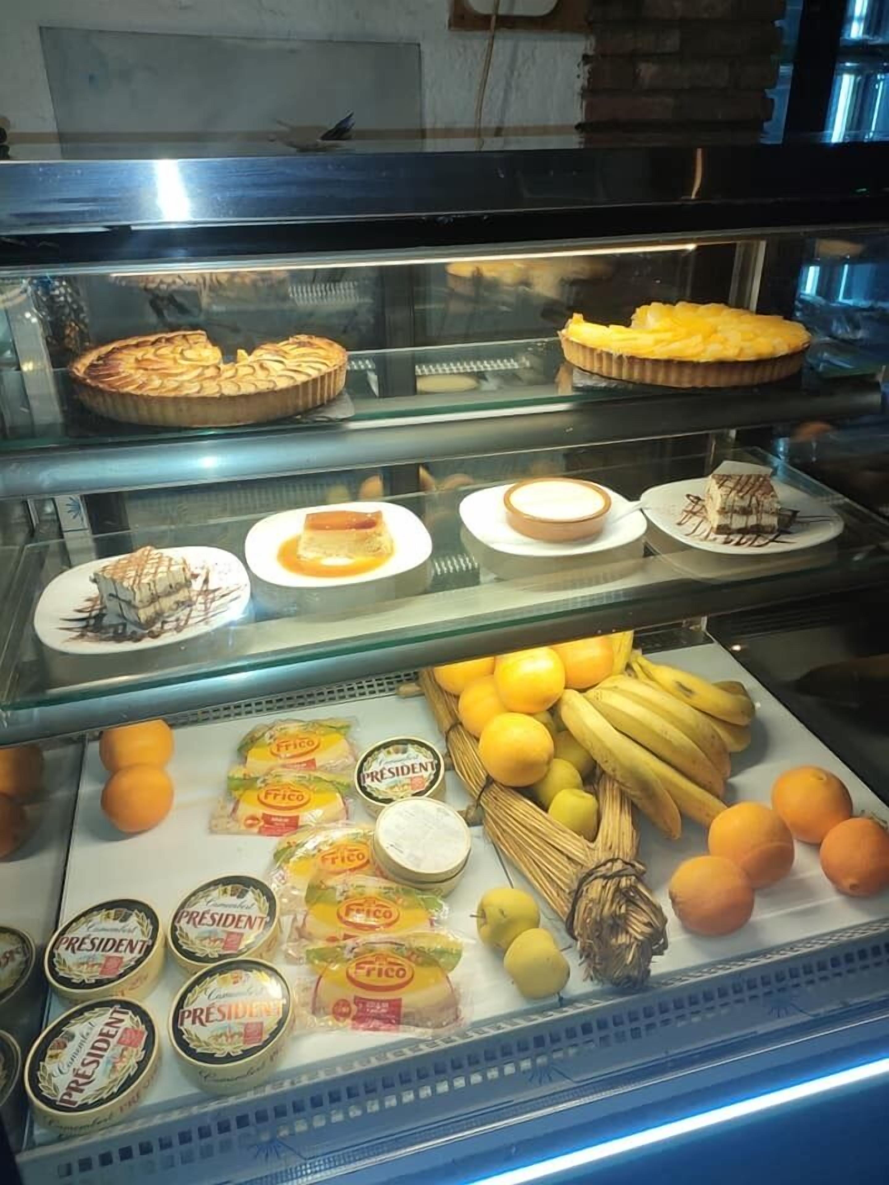 Vitrine de padaria com diversos produtos de panificação e frutas frescas.