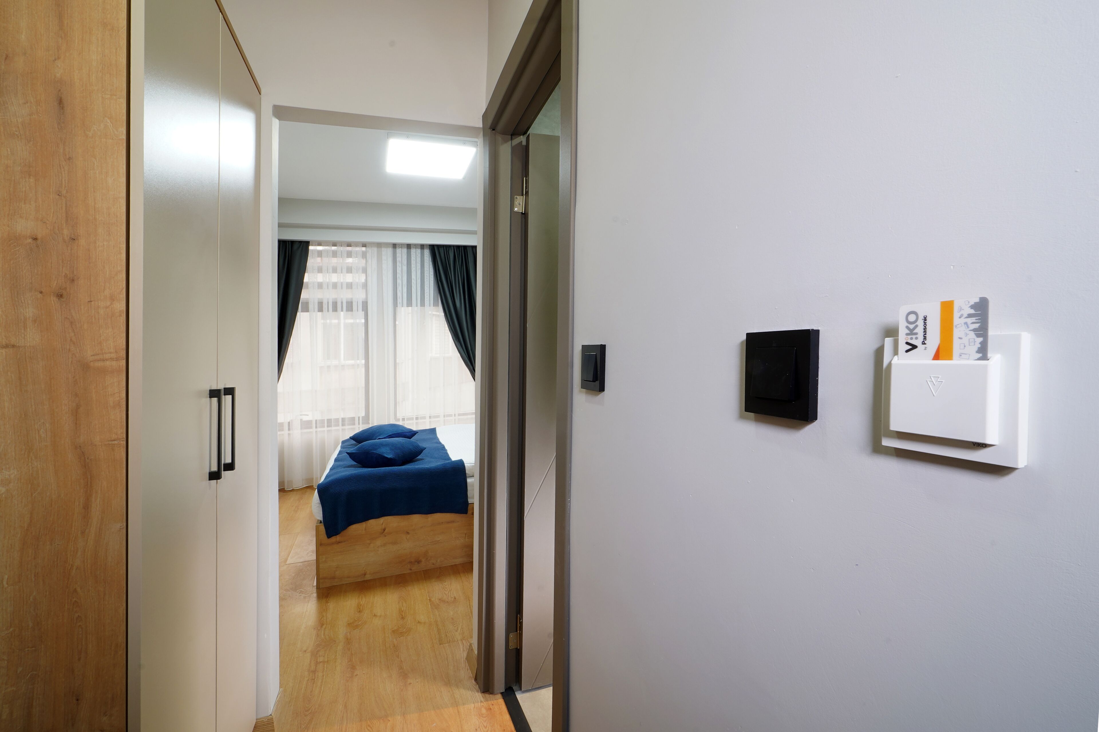Quarto de hotel com cama, guarda-roupa e termostato fixado na parede.