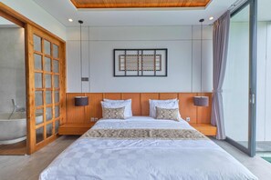 Quarto moderno com cama grande, cabeceira de madeira e um banco embutido.