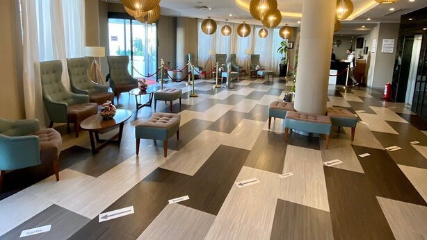 Um lobby amplo com design moderno, com diferentes áreas de estar e um balcão de recepção.