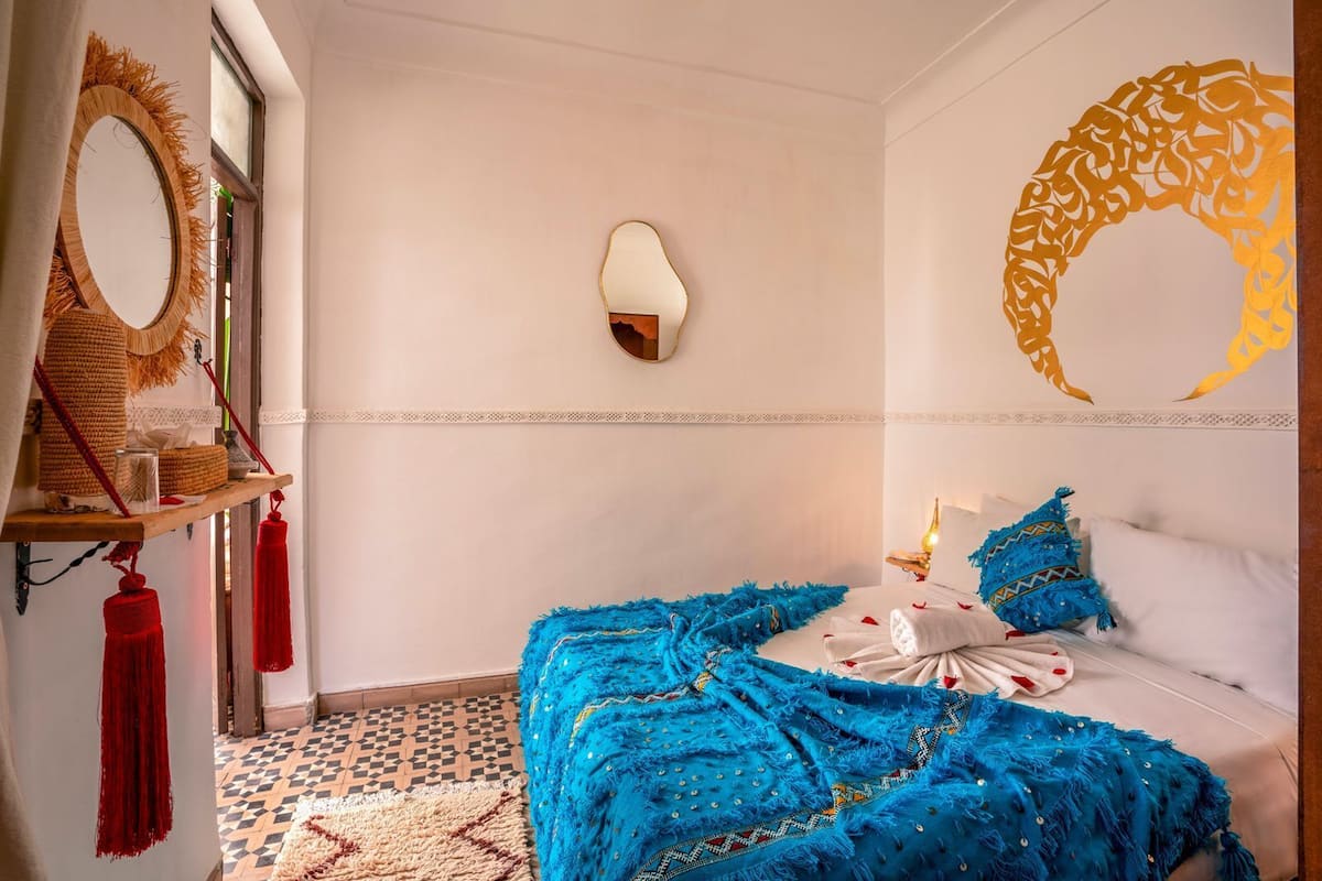 Quarto com cama, espelho fixado na parede, elemento decorativo na parede e piso estampado.