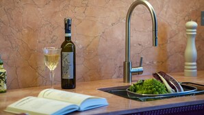 Uma bancada de cozinha com uma garrafa de vinho, um copo de vinho e um livro.