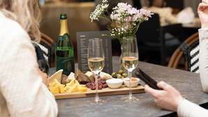 Uma mesa com uma garrafa de vinho, um menu e um copo de vinho branco.