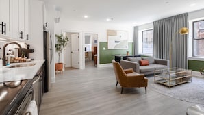 Um apartamento moderno com cozinha, sala de estar e espaço de jantar. Possui um sofá, uma mesa de centro e uma mesa de jantar.