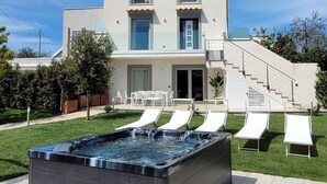 Uma casa moderna de dois andares com piscina, área de estar externa e ofurô.