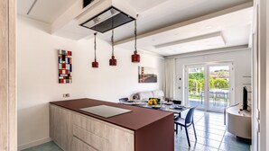 Uma cozinha moderna com uma ilha central, luminárias pendentes e uma área de refeições com vista para o exterior.