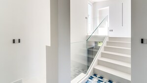 Uma escadaria moderna com guarda-corpos de vidro e um chão com padrão geométrico.