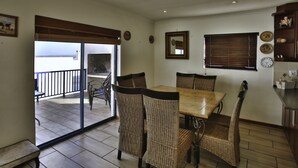 Uma área de refeições com mesa e cadeiras, vista para o exterior, e uma cozinha com armários e bancada.
