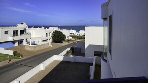 Um edifício moderno com vista para o mar e montanhas ao longe.