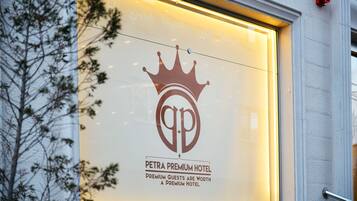 Placa de hotel com logotipo de coroa e o texto 'PETRA PREMIUM HOTEL' e 'Hóspedes premium merecem um hotel premium'.