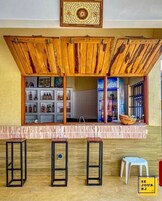 Uma área de bar com painéis de teto de madeira, prateleiras com garrafas e bancos.