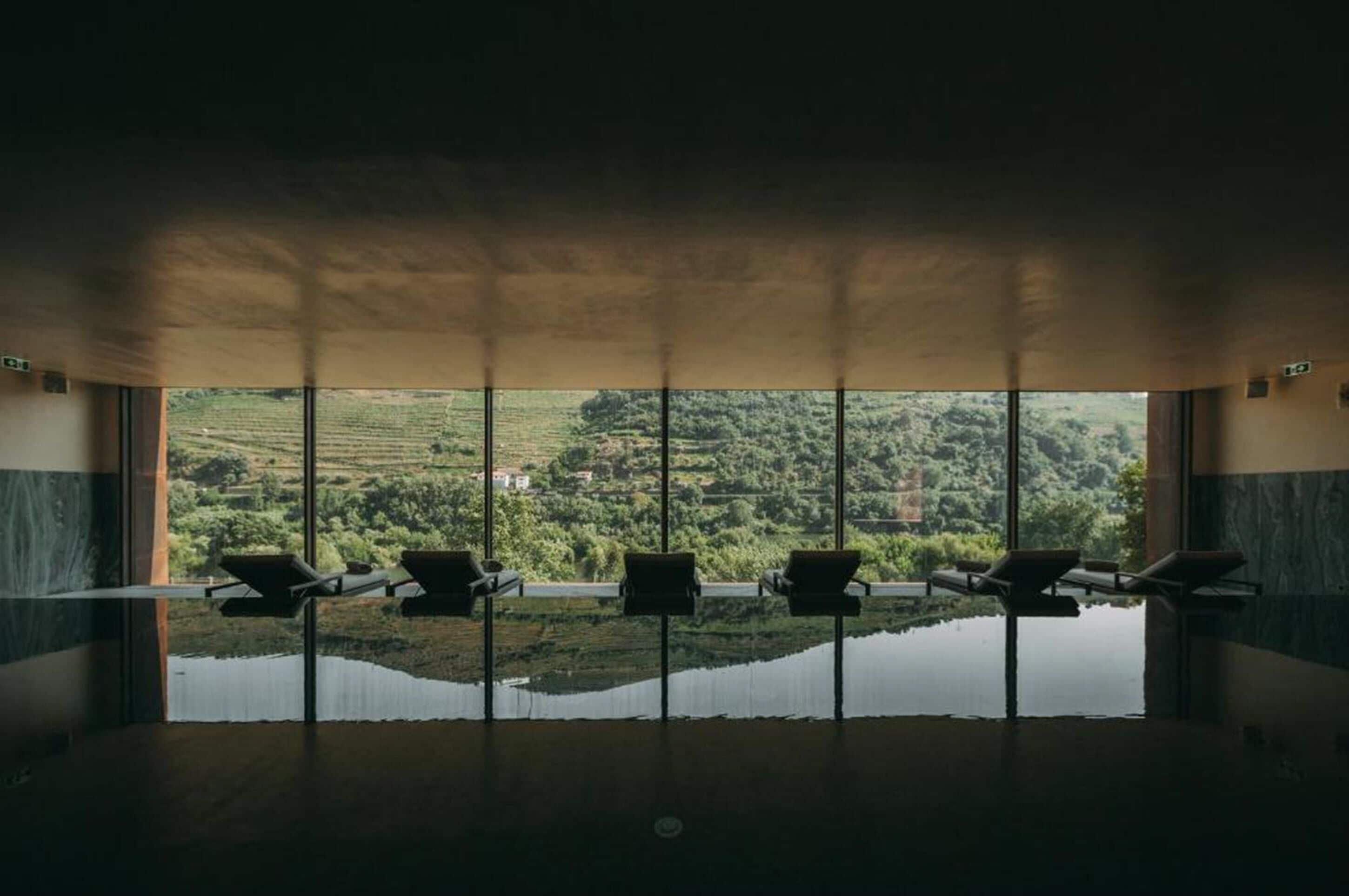 Quarto com uma janela grande que dá para a paisagem, com piscina e várias espreguiçadeiras.
