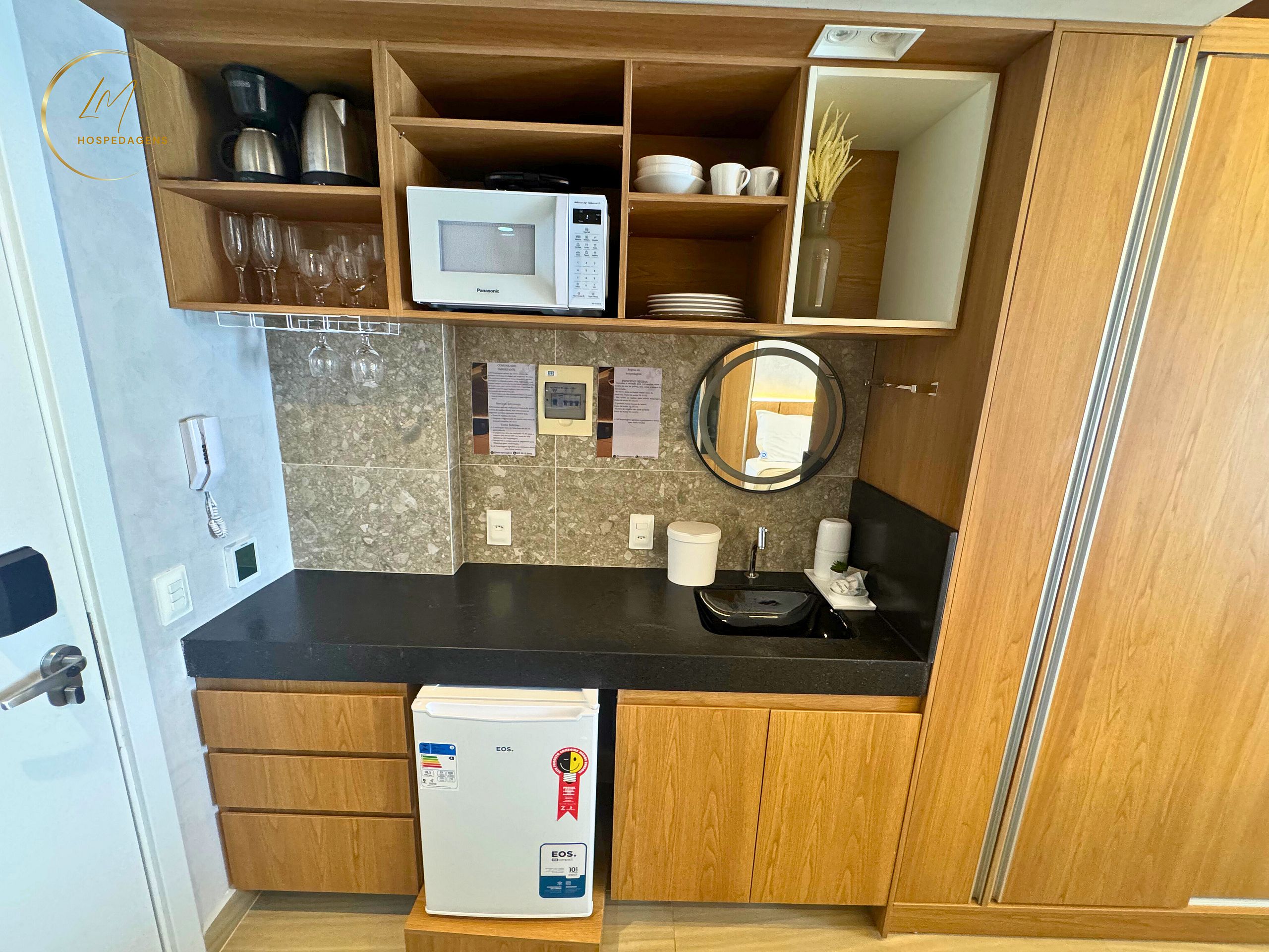 Uma cozinha compacta equipada com micro-ondas, cafeteira e pequena geladeira.