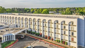 Um edifício grande com uma fileira de janelas em arco e uma área de estacionamento coberta.