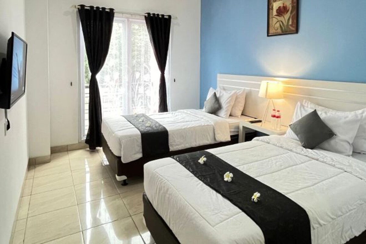Quarto de hotel com duas camas, televisão, janela com cortinas e um quadro na parede.