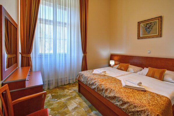 Quarto de hotel com uma cama, uma escrivaninha e uma cadeira.