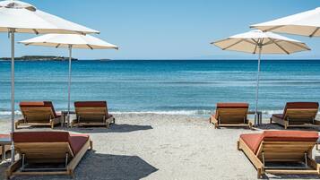 Na praia, espreguiçadeiras, guarda-sóis, toalhas de praia