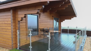 Uma cabana de madeira com porta de vidro que dá para um deck.