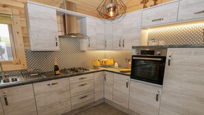 Cozinha moderna com armários de madeira clara, fogão a gás, forno e painel de fundo estampado.