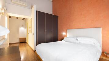 Quarto com cama, guarda-roupa, mesa de cabeceira e abajur.