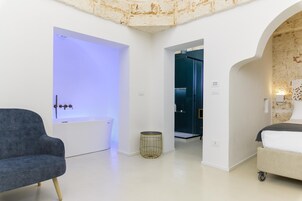 Quarto moderno com uma janela grande, uma banheira, uma cama e uma cadeira.