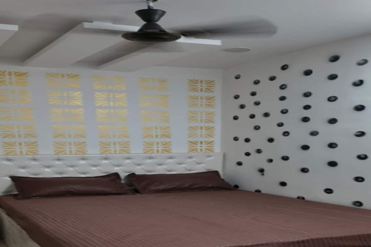 Quarto com cabeceira estofada, cama com roupa de cama castanha, ventoinha no teto e decorações de parede estampadas.