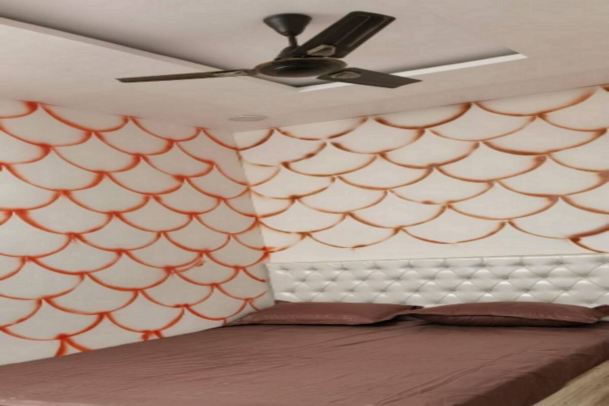 Quarto com cama, ventilador de teto e parede estampada.