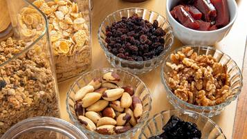Diversos alimentos como frutos secos, fruta desidratada e granola dispostos sobre uma mesa.