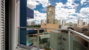 Um edifício alto com fachada de vidro e vista para o horizonte urbano, incluindo uma torre imponente.