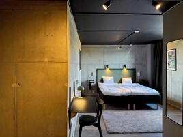 Quarto de hotel moderno com uma cama grande, uma escrivaninha e uma cadeira.