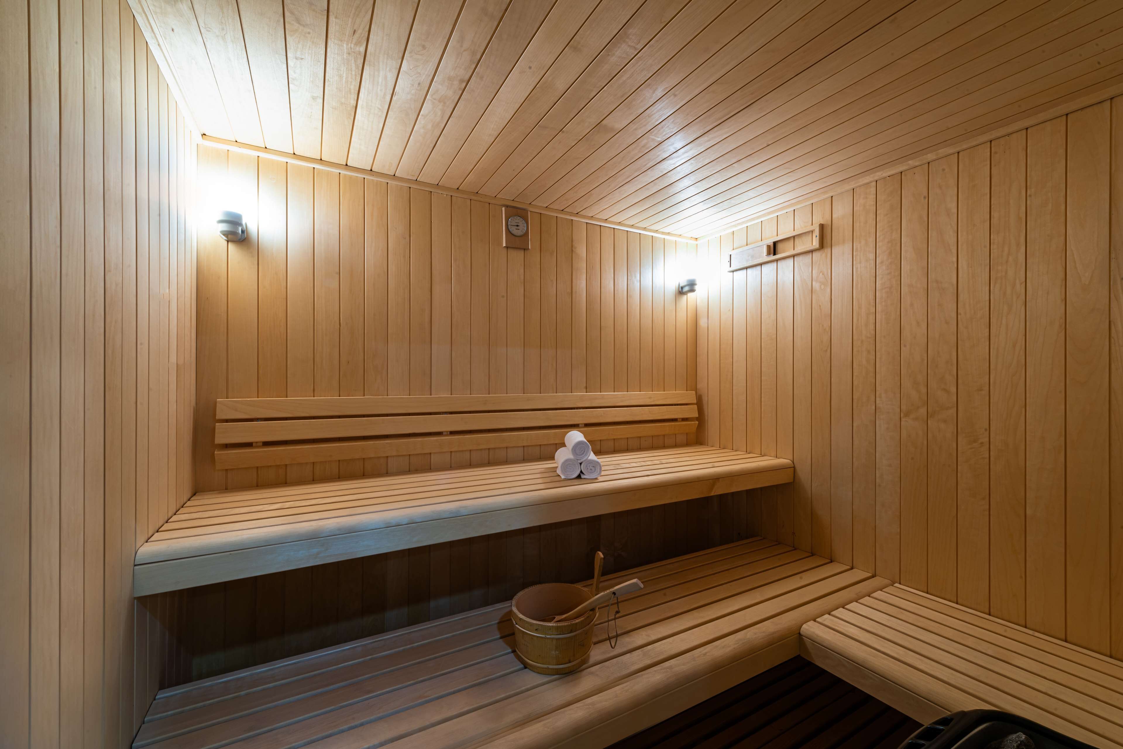 Uma sauna de madeira com bancos e um balde.