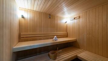 Uma sauna de madeira com bancos e um balde.